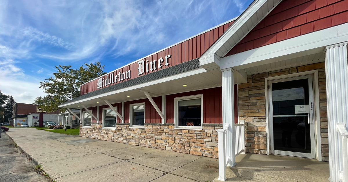 the front view of the middleton diner, a classic american eatery, with its red and white façade, stone accents, and welcoming entrance under clear blue skies