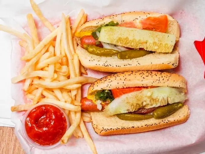 The holy trinity of fast food: a perfectly dressed dog, crispy fries, and a refreshing drink. It's comfort on a tray!