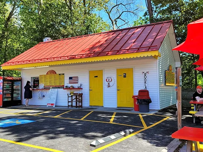 A cheerful white building with sunny yellow doors beckons like a summer postcard come to life. The red metal roof adds a perfect pop of Maine charm.
