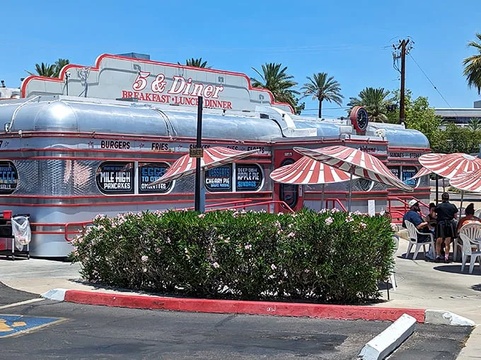 Chrome gleams and neon dreams: The 5 & Diner's exterior shimmers like a time capsule from 1955, complete with retro-striped awnings and desert palm trees. Photo credit: Guido Haesen