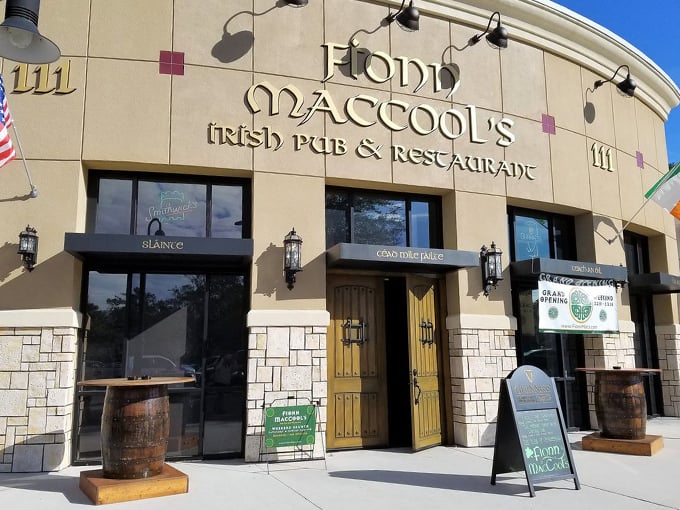 Welcome to Ireland... in Florida? Fionn MacCool's exterior blends Irish charm with Sunshine State flair, complete with wooden barrels and a cheeky chalkboard sign. Photo credit: Fionn MacCool’s Irish Pub & Restaurant