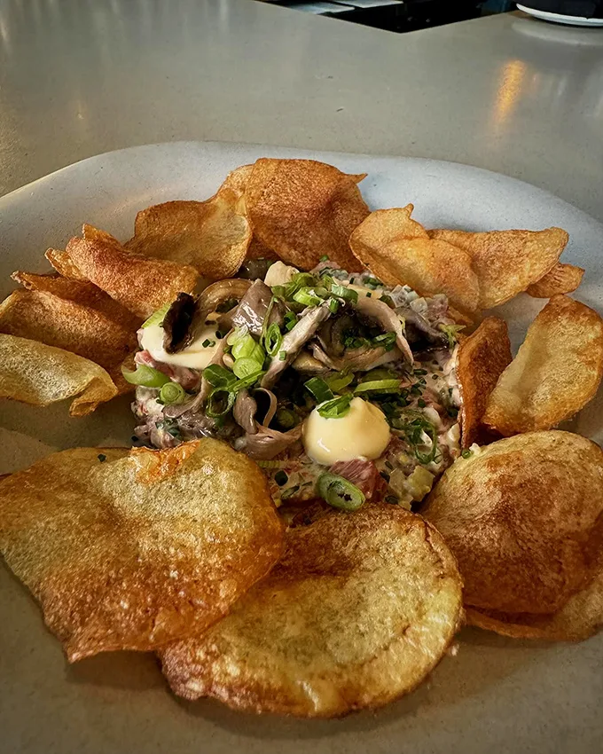 House-made potato chips surround their prize: a perfectly seasoned tartare that's ready for its close-up.