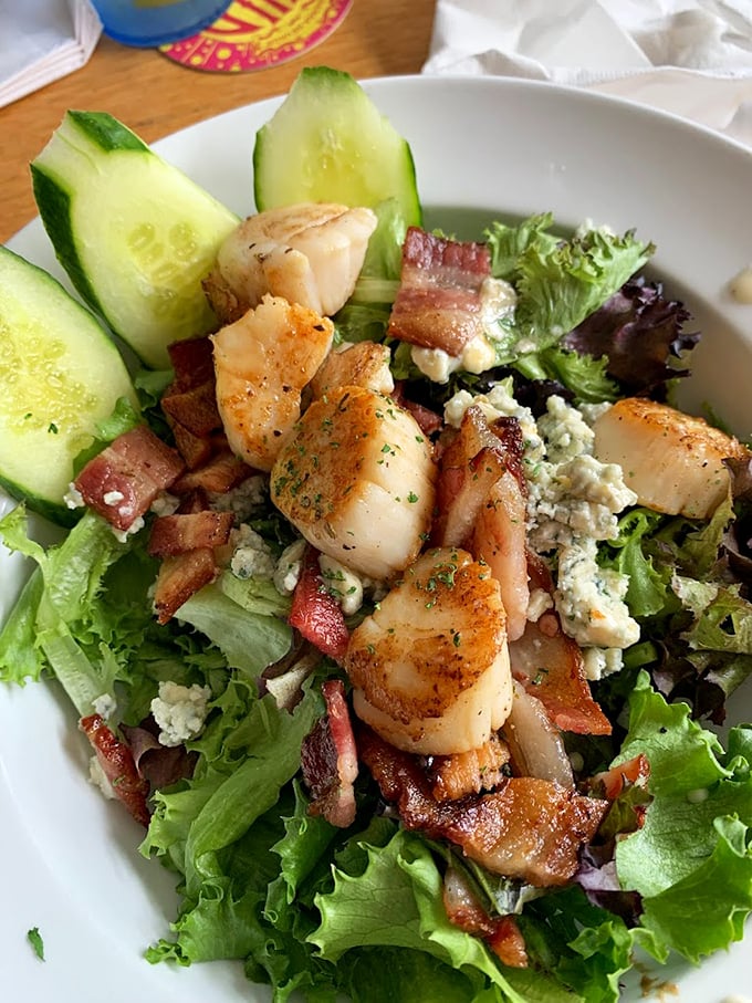 Garden-fresh greens playing host to perfectly seared scallops and crispy bacon – a salad that means business. Photo credit: Alison L.