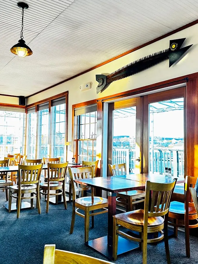 Where every seat comes with a million-dollar view: Floor-to-ceiling windows frame Rockland Harbor while that vintage saw art adds just the right touch of maritime whimsy. Photo credit: Jess Justice