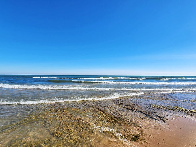 Gentle waves lap against sandy shores while towering bluffs stand guard over Lake Michigan's endless blue horizon.
