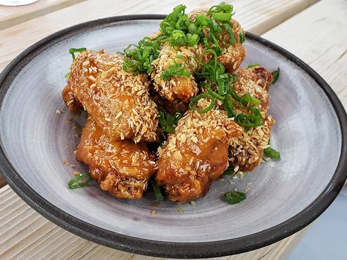 These aren't your average wings – they're dressed to impress with a golden glaze and a shower of fresh herbs. Photo credit: Josh Koelker