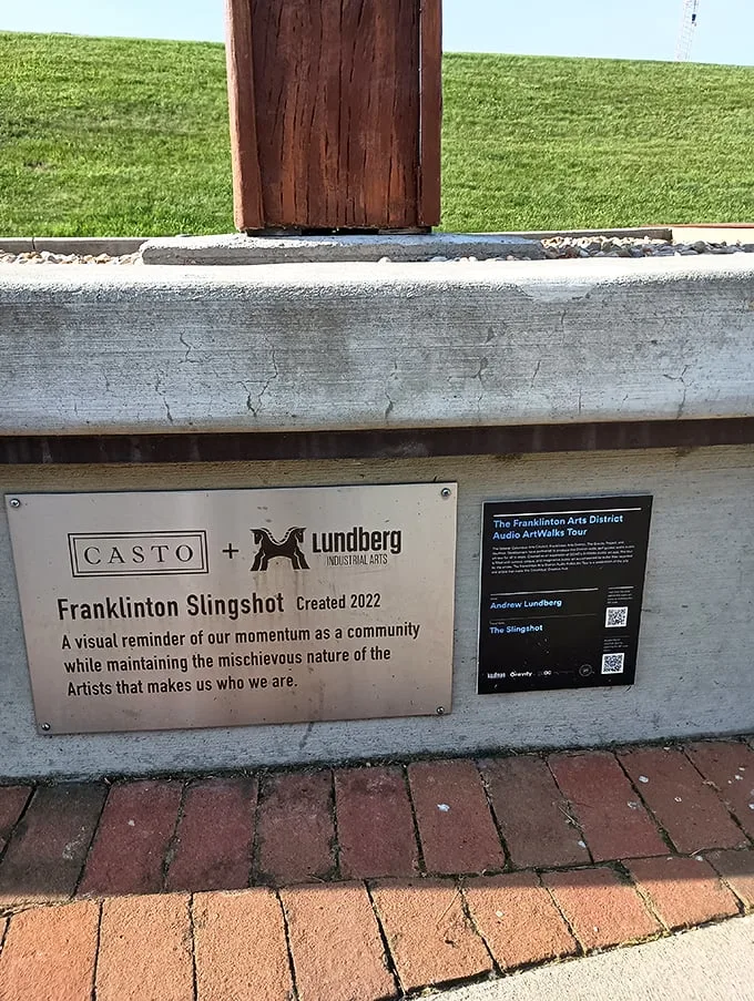 The plaque tells a tale of community spirit and artistic mischief. It's like a motivational poster, but way cooler and with 100% more slingshot.