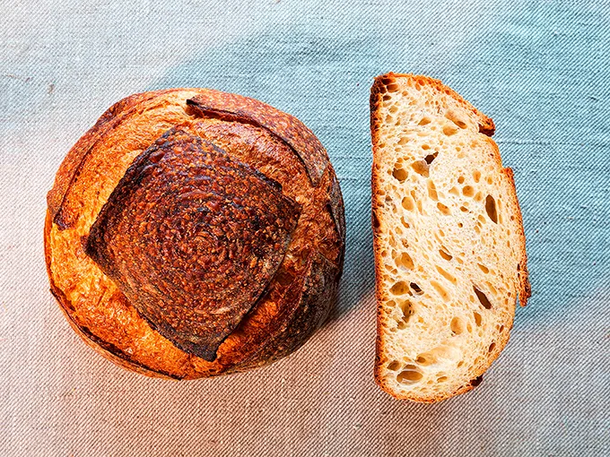 A perfectly crusty sourdough boule with an open crumb that would make Paul Hollywood proud. Photo credit: Beach Pea Baking Co