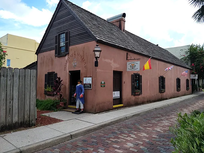 Pink perfection on a cobblestone street! This charming facade is like a dollhouse for history buffs – complete with hanging baskets and colonial flair.