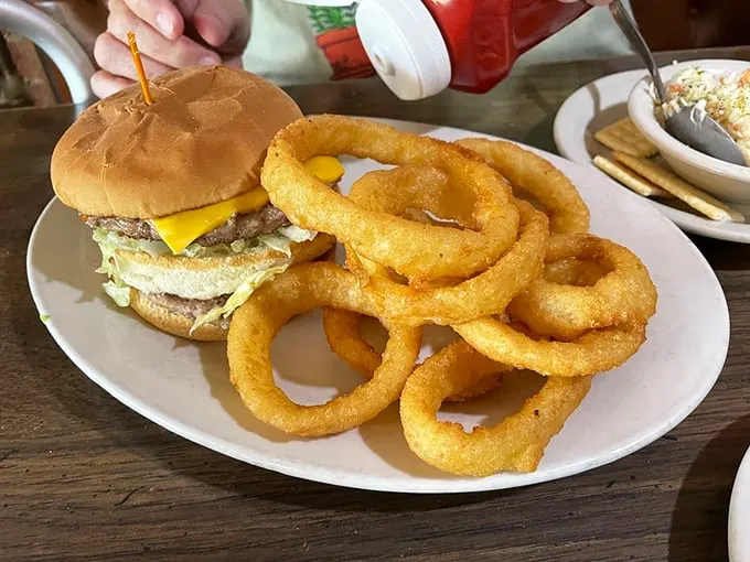 A burger that could make vegetarians question their life choices, paired with onion rings that crunch louder than your diet plans.