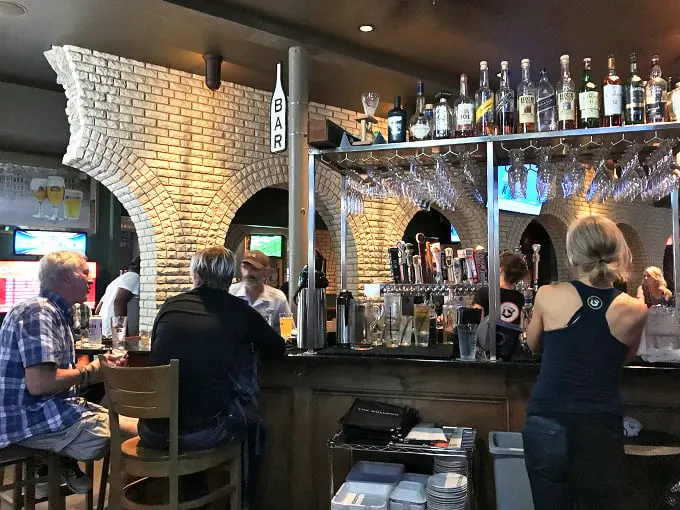 Patrons are enjoying drinks and conversation. The warm lighting and bustling atmosphere create an inviting ambiance.