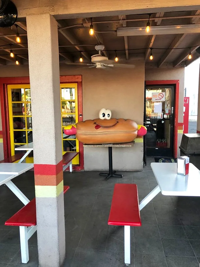 Outdoor seating with a side of whimsy. That hot dog statue is giving me serious "American Gothic" vibes, but tastier.