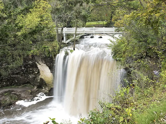 Nature's own waterfall selfie! Minneopa Falls cascades with the grace of a Hollywood starlet, framed by a picturesque bridge and lush greenery.