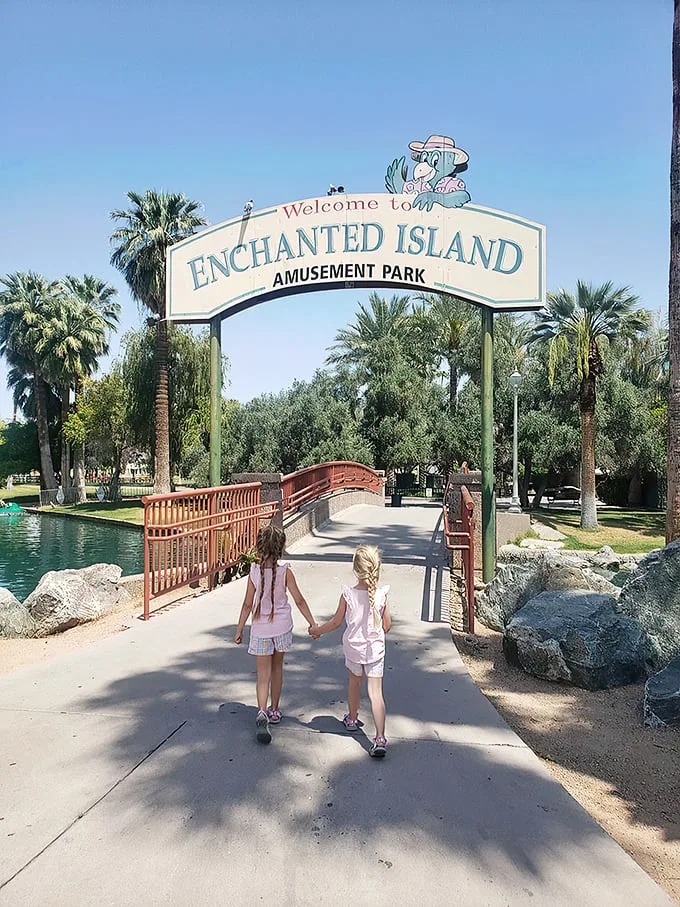 Welcome to Enchanted Island Amusement Park. Palm trees frame the scene, creating an oasis-like atmosphere that promises fun and adventure ahead.