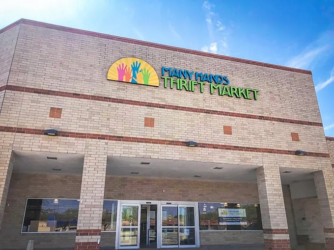 Welcome to the Promised Land of Pre-Loved Treasures! Many Hands Thrift Market's exterior beckons bargain hunters with its colorful logo and promise of hidden gems within.