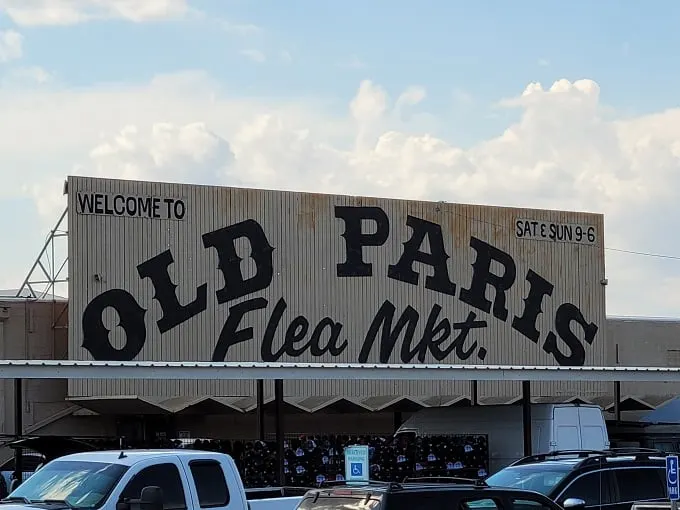 Welcome to the treasure hunter's paradise! Old Paris Flea Market beckons with its retro sign, promising a labyrinth of curiosities and bargains inside.