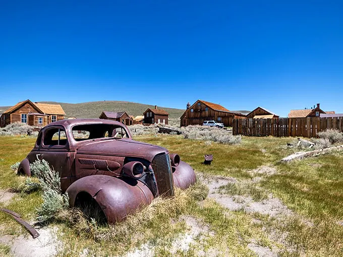 "Rust never sleeps, but this old jalopy sure does!" A weathered vintage car rests peacefully among wooden buildings, telling tales of Bodie's golden days.