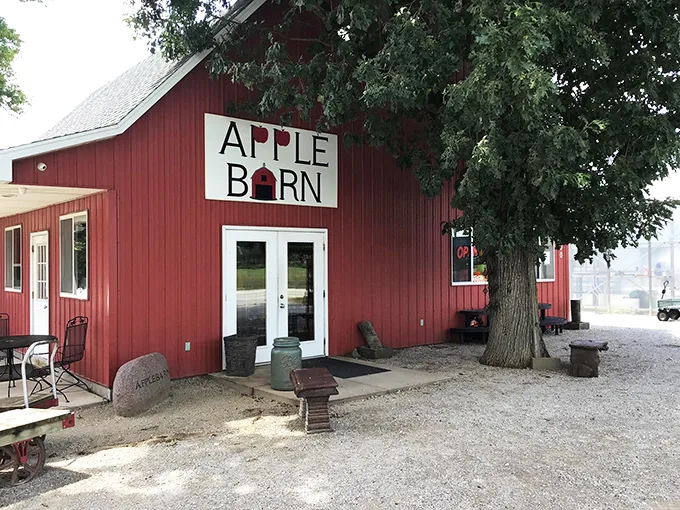 Welcome to apple paradise! The Apple Barn's iconic red exterior promises a cornucopia of orchard delights, with autumn's bounty spilling onto the porch.