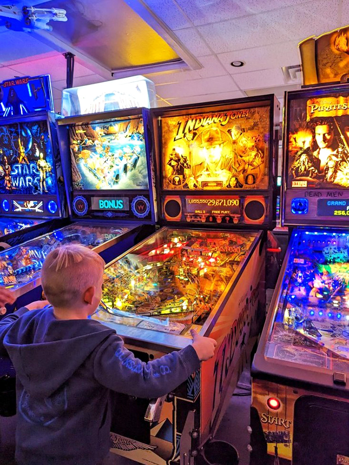 Witness the torch of gaming passion being passed down. This little maestro's already mastering the flipper dance – future pinball wizard in the making!