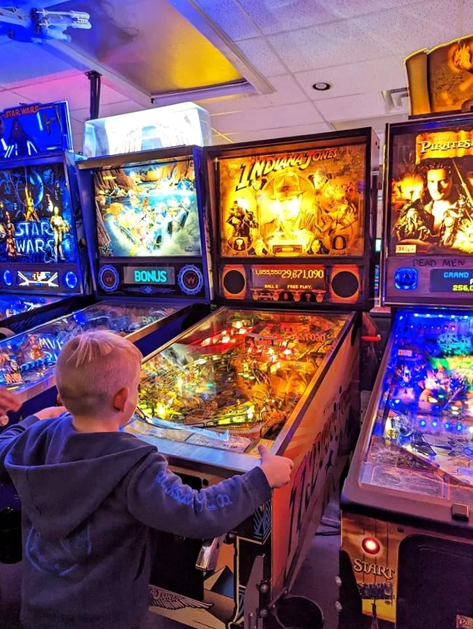 Witness the torch of gaming passion being passed down. This little maestro's already mastering the flipper dance – future pinball wizard in the making!