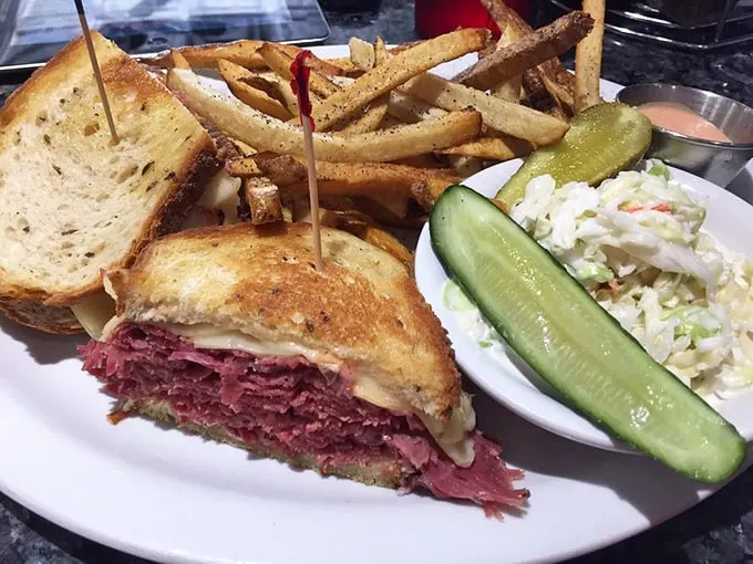 The Reuben that ate Manhattan! This towering sandwich, flanked by crispy fries and tangy slaw, is a meal fit for a king – or a very hungry commoner.