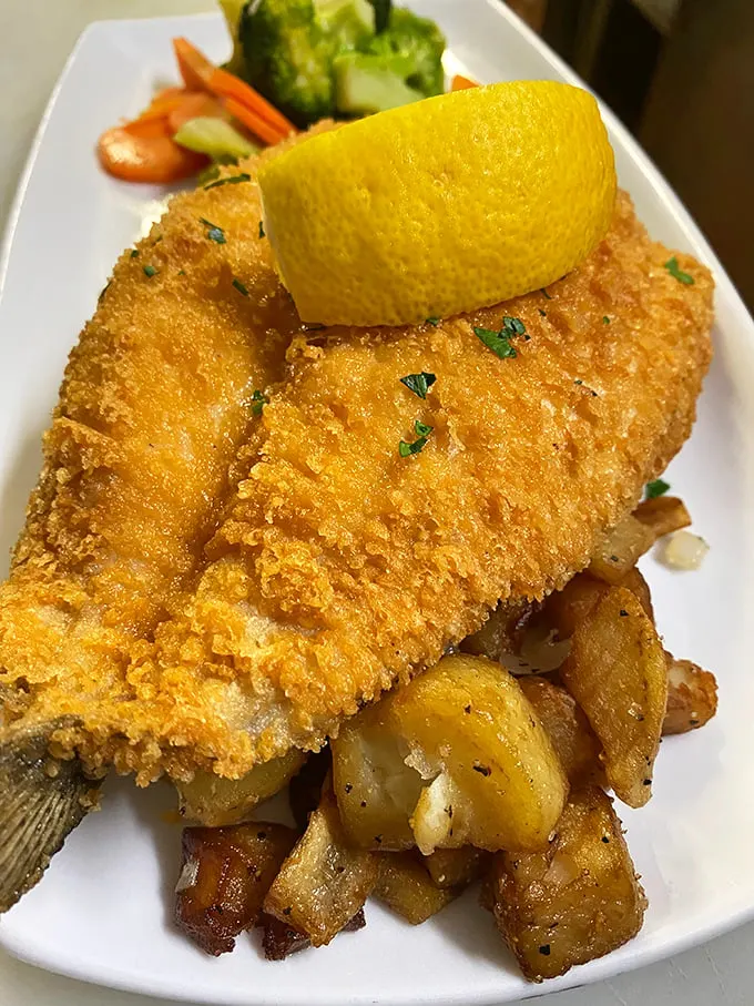 Golden-crusted fish that would make Poseidon himself jealous. Perched atop a bed of crispy potatoes, it's a seafood lover's dream come true.
