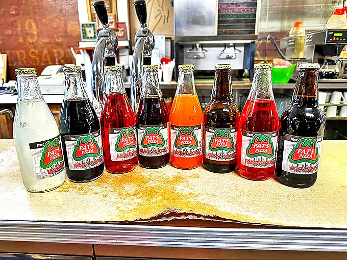"Pat's own soda lineup: Bubbles of joy in every sip!" These colorful bottles are like a liquid rainbow, ready to complement your pizza adventure.