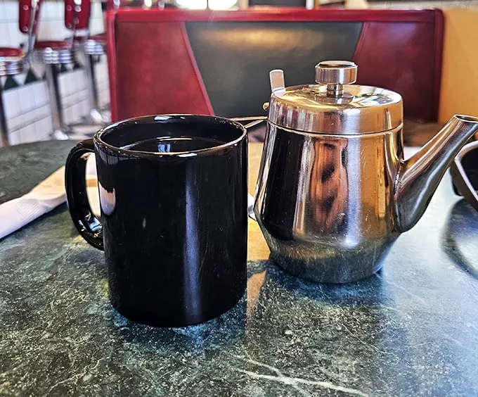 The dynamic duo of diner dining: A steaming cup of joe and a classic silver pot. Name a more iconic breakfast pair – I'll wait.