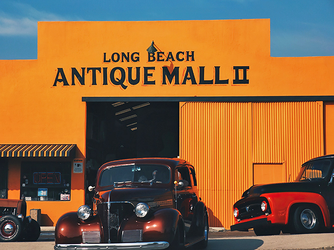 Welcome to the time machine! This vibrant orange facade houses more memories than your grandma's attic, with classic cars that'll make any gearhead swoon.