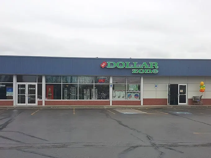 The iconic blue and green Dollar Zone sign beckons like a budget-friendly lighthouse in Anchorage's retail sea. Bargain hunters, your port awaits!