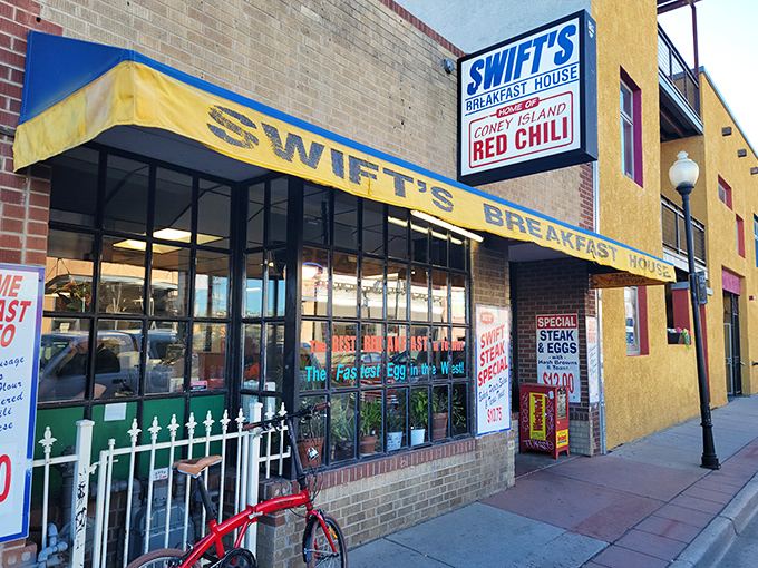 Welcome to flavor town! Swift's Breakfast House stands proud, its yellow awning a beacon of hope for hungry souls seeking breakfast bliss in Denver.