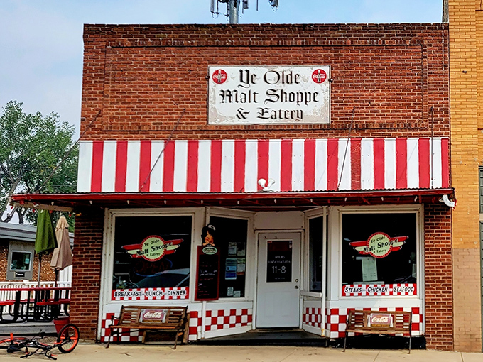 Step back in time at Ye Olde Malt Shoppe, where the red-and-white awning promises a sweet escape from the modern world. It's like finding a portal to the 1950s, complete with checkered charm!