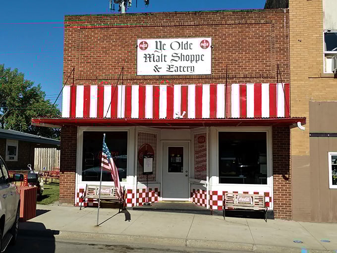 Step back in time at Ye Olde Malt Shoppe, where the red-and-white awning promises a sweet escape from the modern world. It's like finding a portal to the 1950s, complete with checkered charm!
