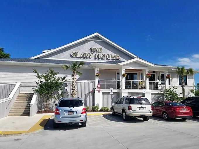 Welcome to seafood paradise! The Claw House stands proud, a beacon of deliciousness with its crisp white exterior and inviting palm trees.