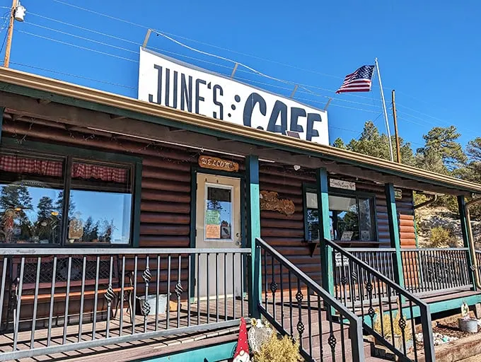 The log cabin charm of June's Cafe stands proudly against Arizona's blue sky, complete with American flag – a beacon of breakfast hope for hungry travelers.