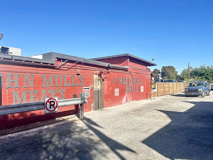 The unassuming red exterior of Road Kill Grill stands like a barbecue beacon in the desert, promising smoky treasures within its humble walls.