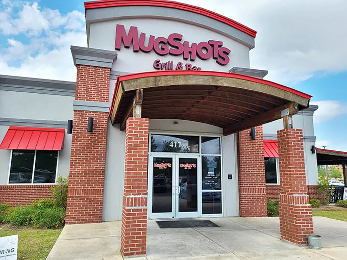 Welcome to flavor town! Mugshots Grill & Bar stands proud, its red awnings beckoning like a culinary lighthouse guiding hungry souls to delicious shores.