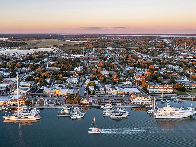Sunset casts golden light over Beaufort's harbor, where sailboats rest after a day at sea and historic homes stand watch along tree-lined streets.