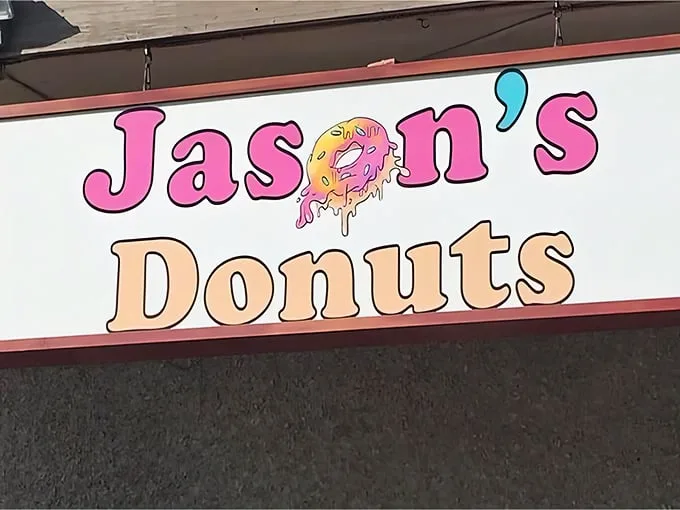A sign that promises sweet dreams! Jason's Donuts beckons with its playful logo, like a Willy Wonka factory for the breakfast crowd.