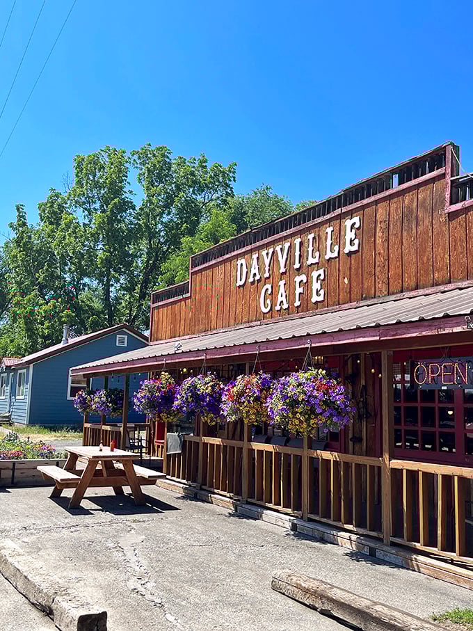 The wooden facade of Dayville Cafe stands proudly against the Oregon sky, hanging flower baskets adding splashes of color like nature's welcome committee.