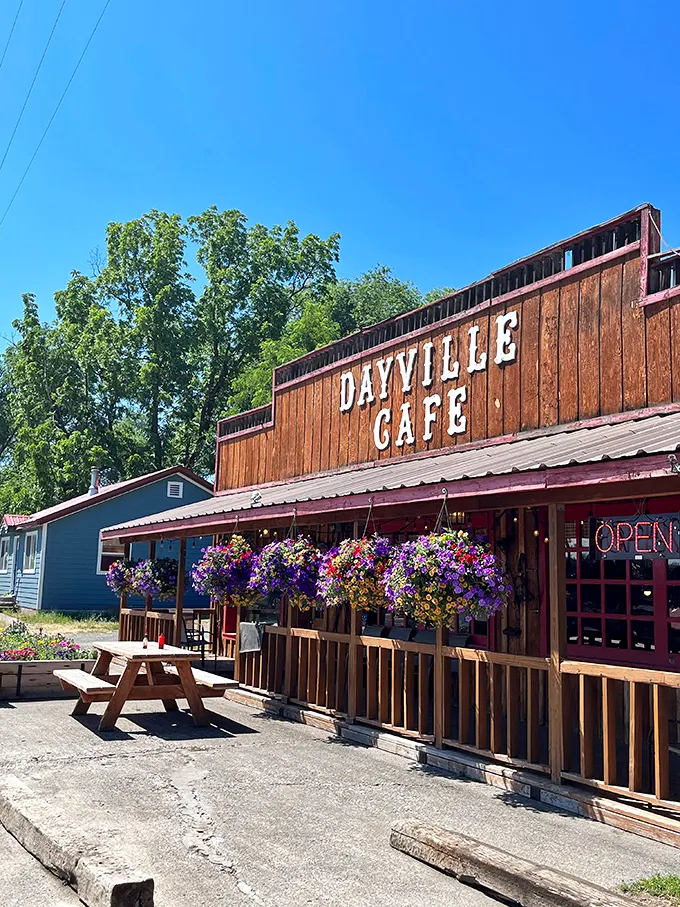 The wooden facade of Dayville Cafe stands proudly against the Oregon sky, hanging flower baskets adding splashes of color like nature's welcome committee.