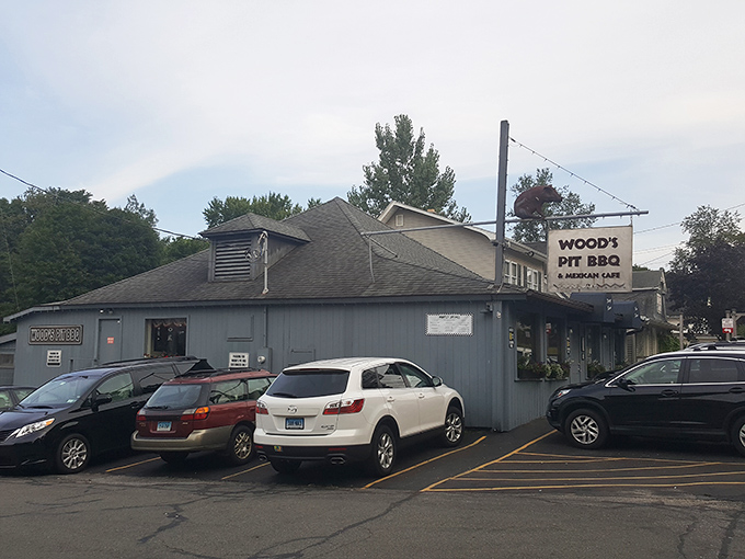 Welcome to BBQ paradise! Wood's Pit BBQ & Mexican Cafe's exterior promises a flavor fiesta, with its charming blue-gray facade and inviting neon cactus sign.