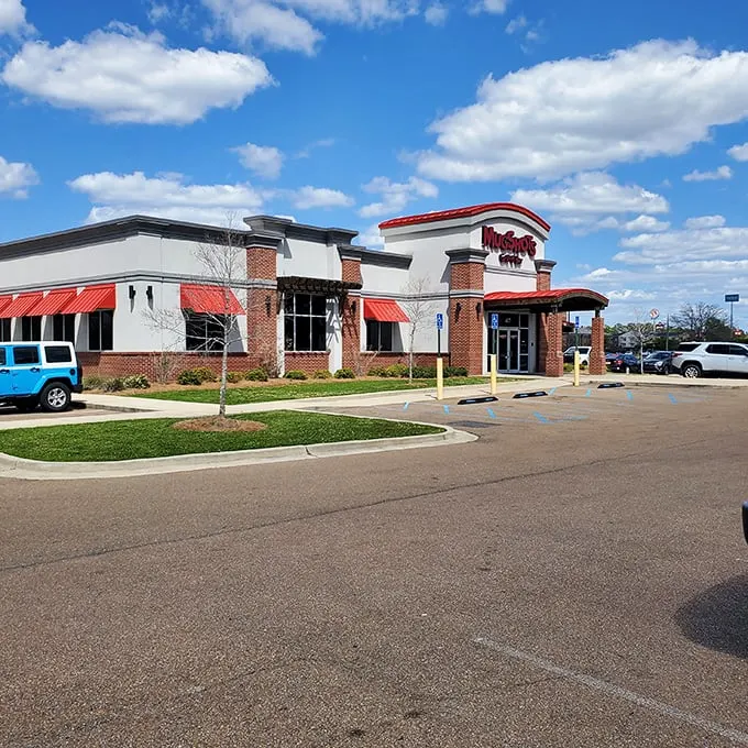 Welcome to flavor town! Mugshots Grill & Bar stands proud, its red awnings beckoning like a culinary lighthouse guiding hungry souls to delicious shores.