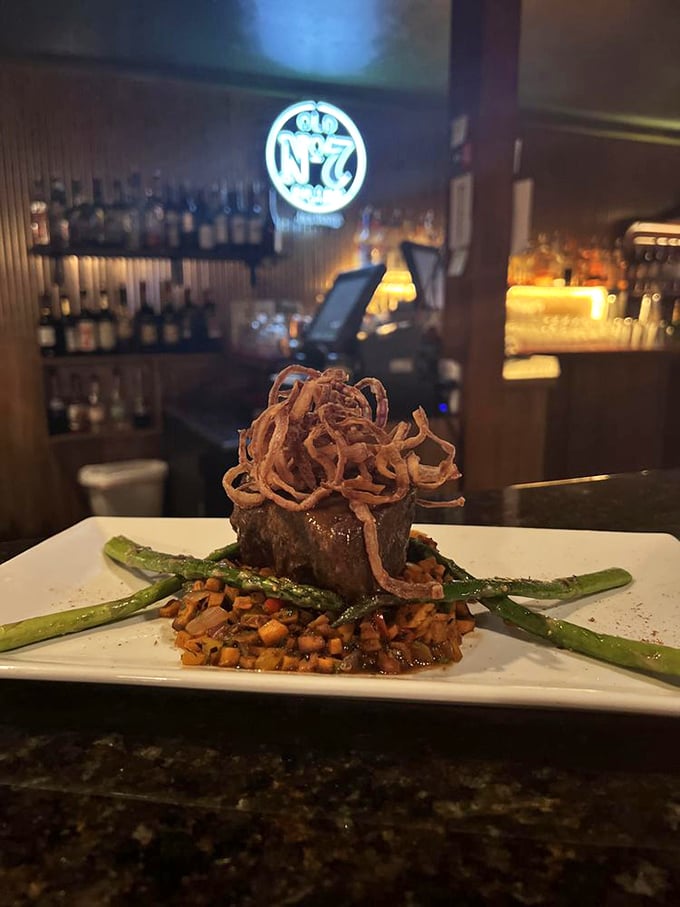 This isn't just a steak—it's architecture. Crispy onion straws crown a perfectly cooked cut, with asparagus soldiers standing guard.