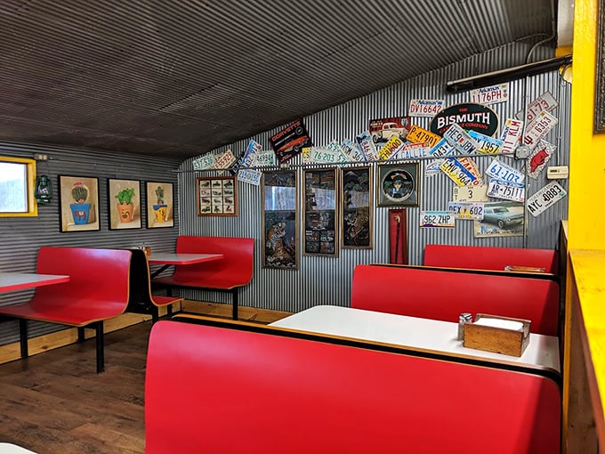 Red booths against corrugated metal walls lined with license plates—it's like sitting inside a time capsule where calories don't count and conversations flow freely.