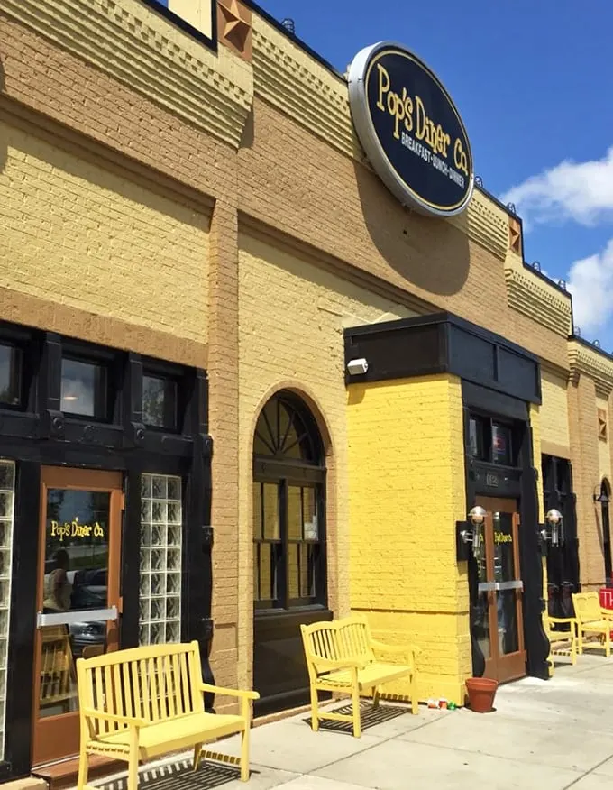 Those yellow benches outside aren't just seating—they're the waiting room for flavor paradise, matching the building's cheerful exterior.