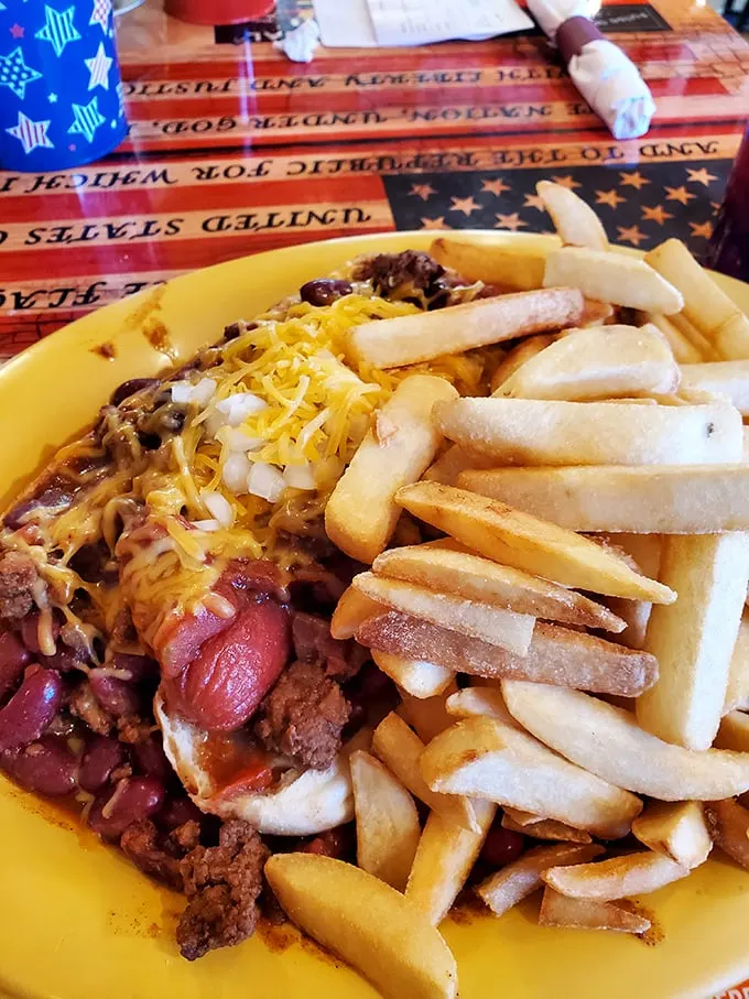 A chili dog that demands both napkins and respect, surrounded by fries that somehow manage to be both supporting actors and co-stars.