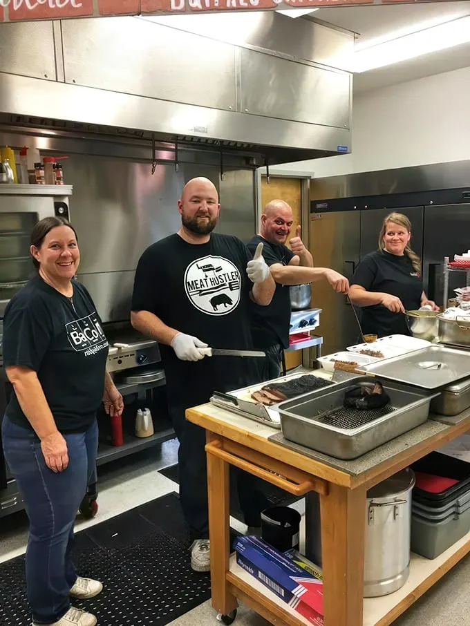 The smoke whisperers themselves—wearing their "Meat Hustler" credentials proudly while orchestrating the slow-dance between fire, smoke, and protein.