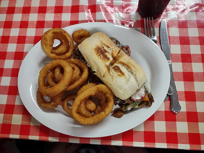 A proper diner sandwich served with golden onion rings—the kind of lunch that makes you wonder why anyone would ever choose a salad.