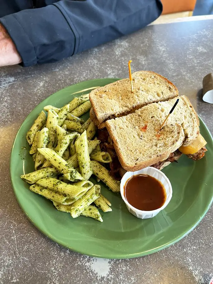 A sandwich that's more stacked than a lumberjack's woodpile, paired with pasta greener than an Alaskan summer. It's a plate of pure comfort.